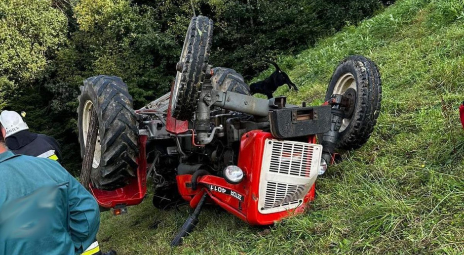 Wypadek na zboczu pola. Rolnik pod ciągnikiem